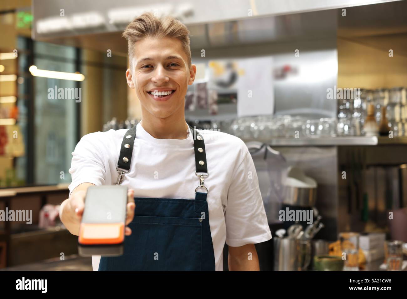 Smiling cafe worker with payment terminal indoors Stock Photo - Alamy
