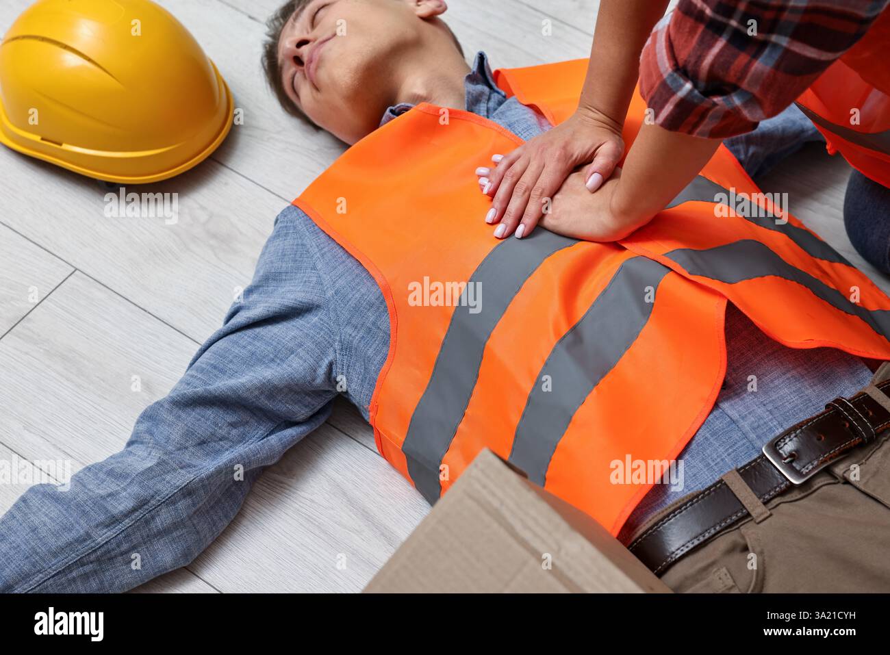 Accident at work. Woman performing CPR on her unconscious colleague in warehouse, closeup Stock ...