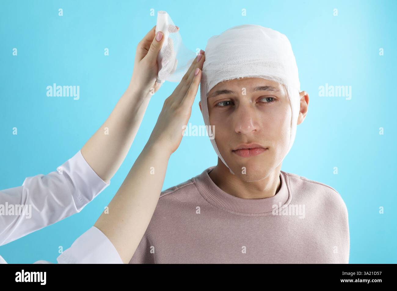 Doctor bandaging patient's head on light blue background, closeup Stock ...