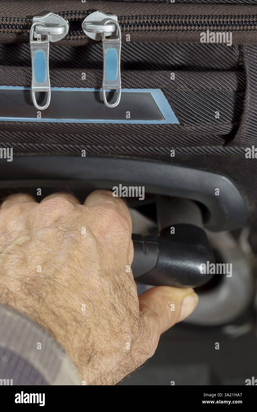 Close-up of a man's hand pushing a black suitcase Stock Photo - Alamy