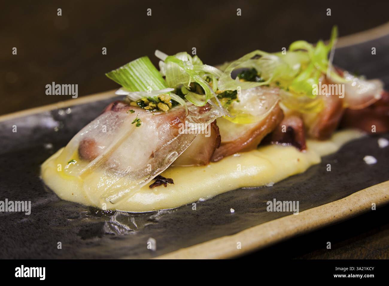 Roasted slices of octopus tentacle on top of a potato puree bed Stock ...