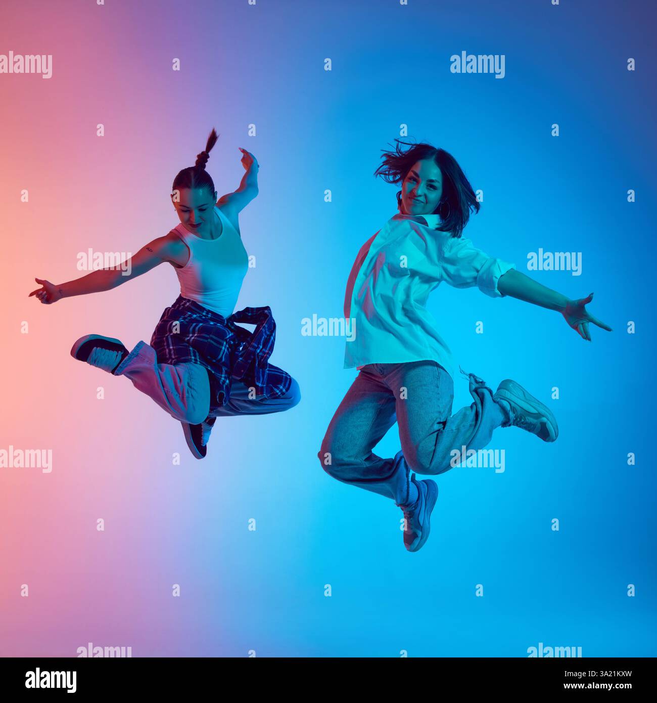 Two young women in casual attire in motion, dynamically dancing hip hop ...
