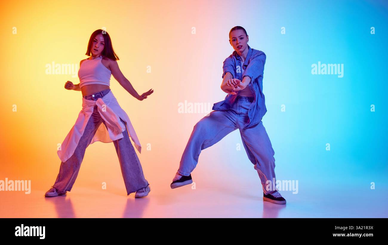 Synchronized hip hop performance by two stylish female dancers against ...