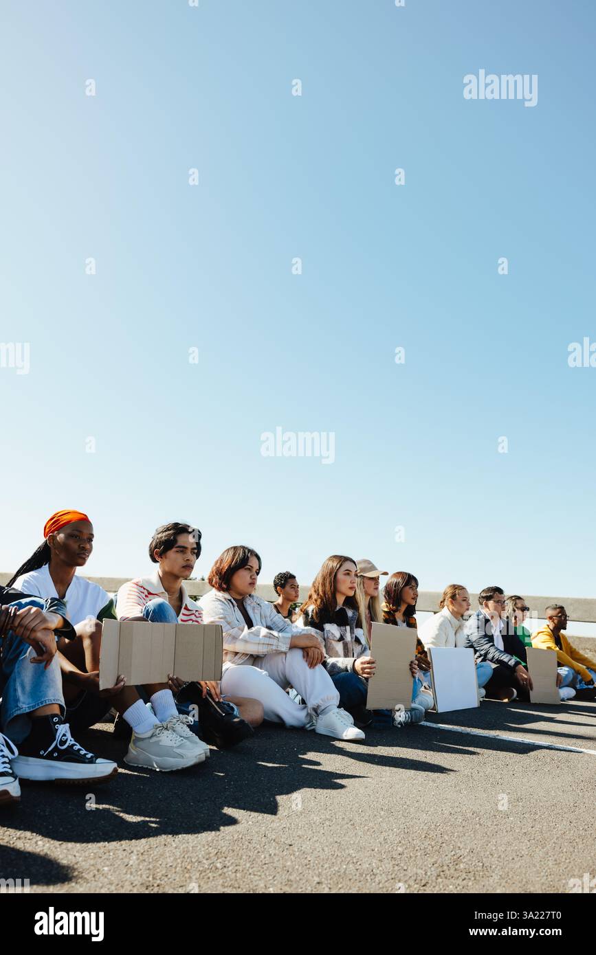 A group of people seated on a road, expressing unity and purpose by ...