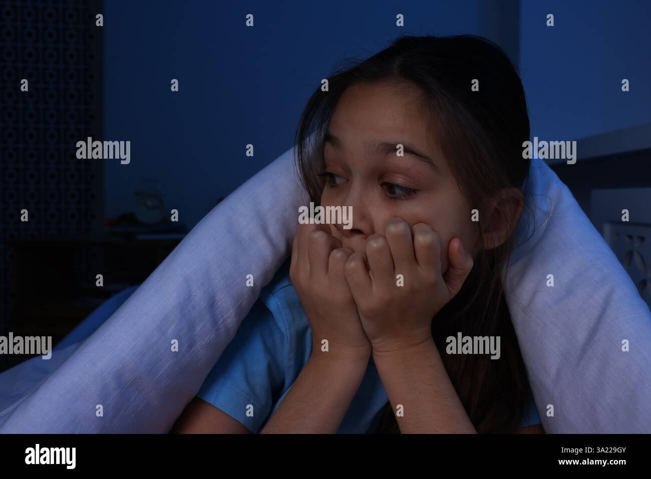 Afraid girl hiding under duvet on bed at night Stock Photo - Alamy