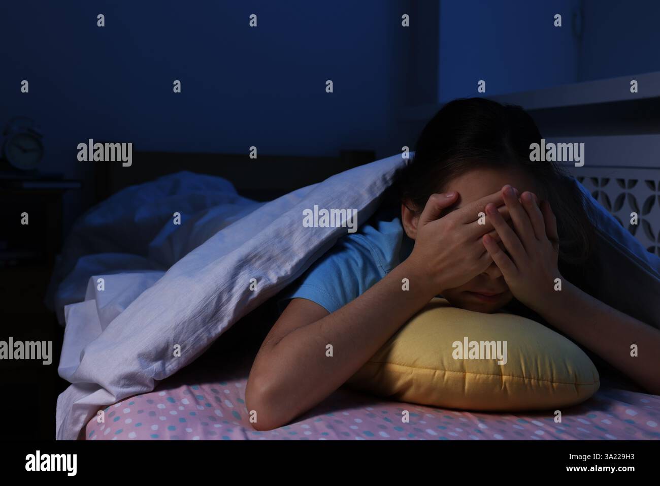 Afraid girl with pillow under duvet on bed at night Stock Photo - Alamy