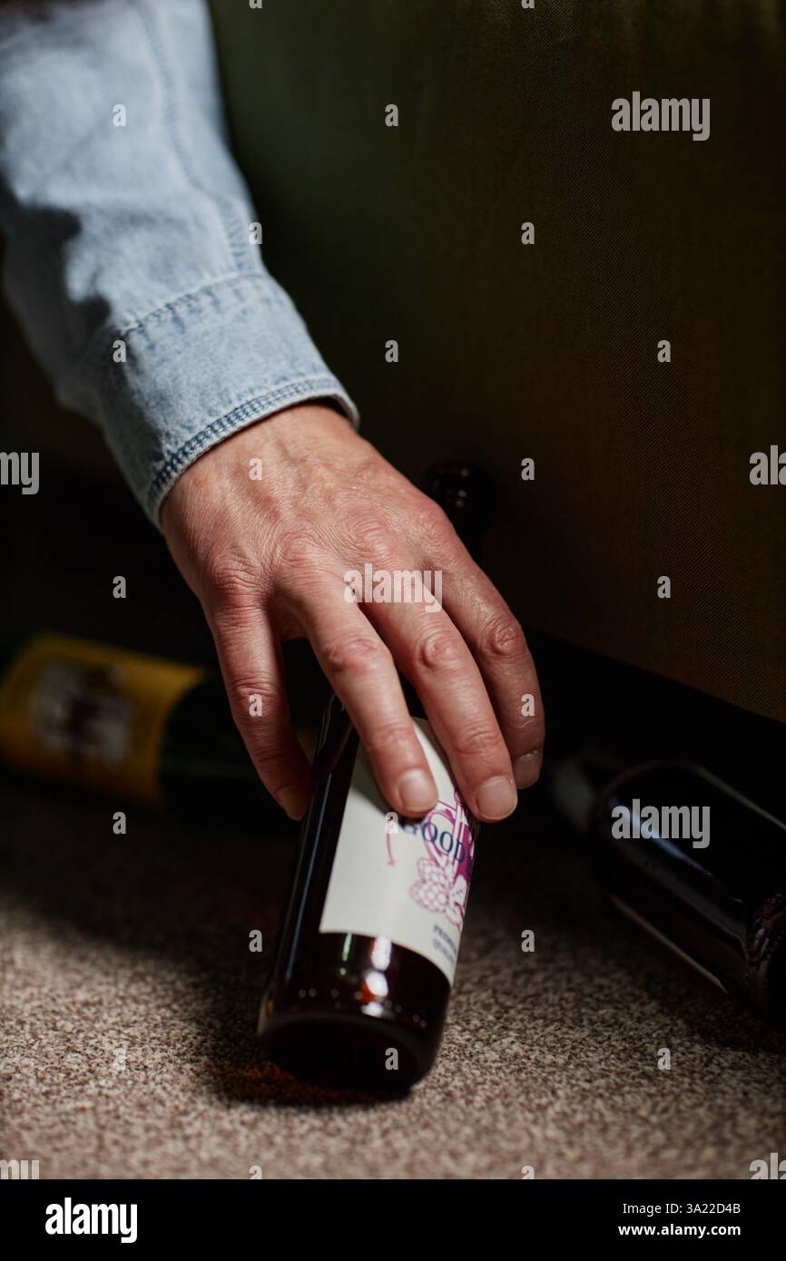Hand reaching under couch grabbing beer bottle with carpet and other ...