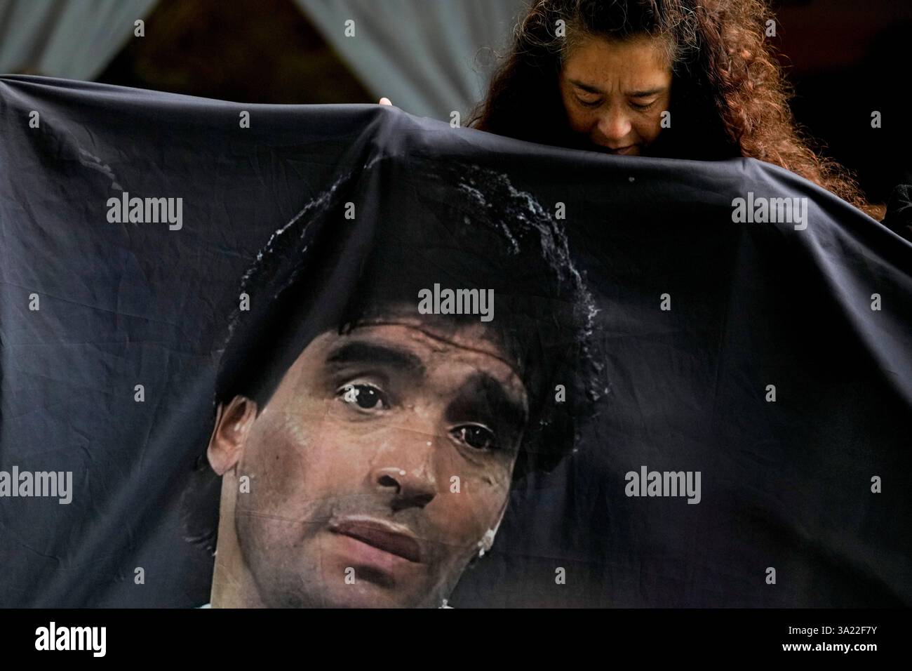 A fan of late soccer star Diego Maradona holds his image outside the ...