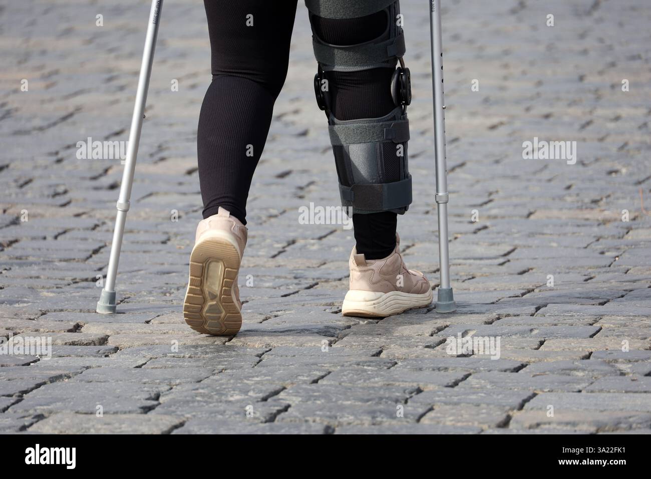 Woman with orthosis walking down the city street. Concept of leg injury ...