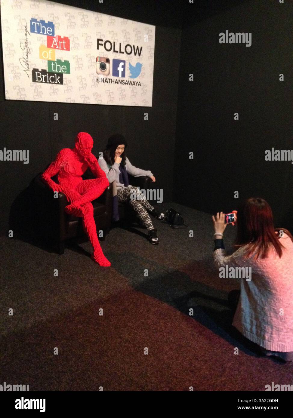the art of the brick exhibition in london- a visitor posing on a bench ...