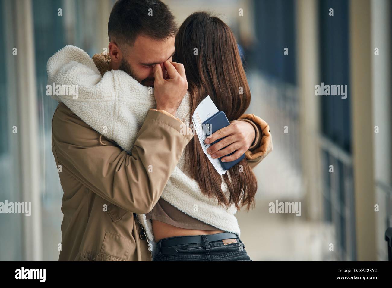 Man is crying, embracing, farewell. Couple are in the airport hall ...