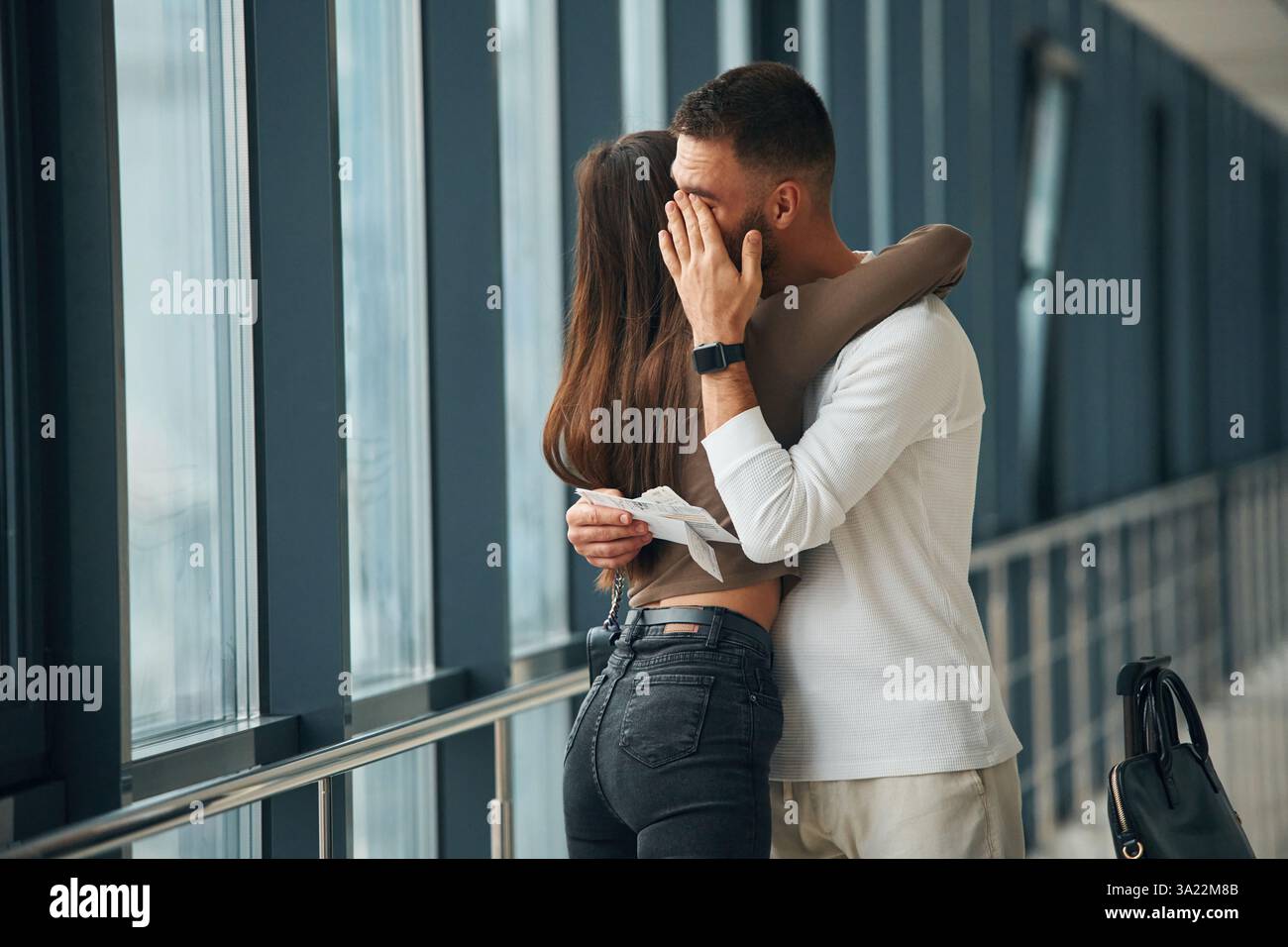 Man is crying, embracing, farewell. Couple are in the airport hall ...
