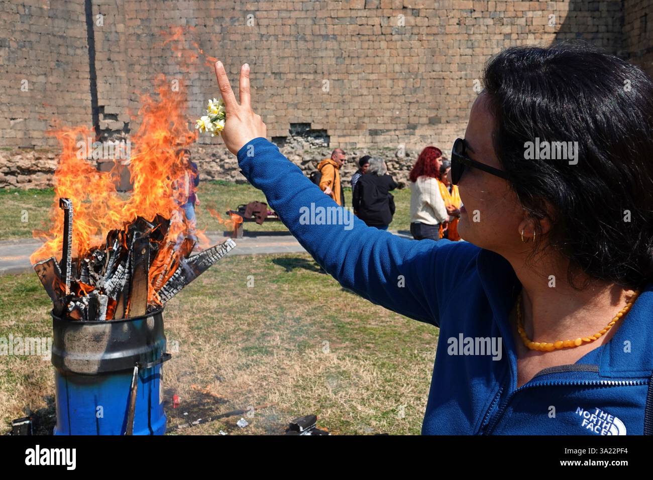 A Kurdish woman makes a victory sign in front of the first Newroz fire ...