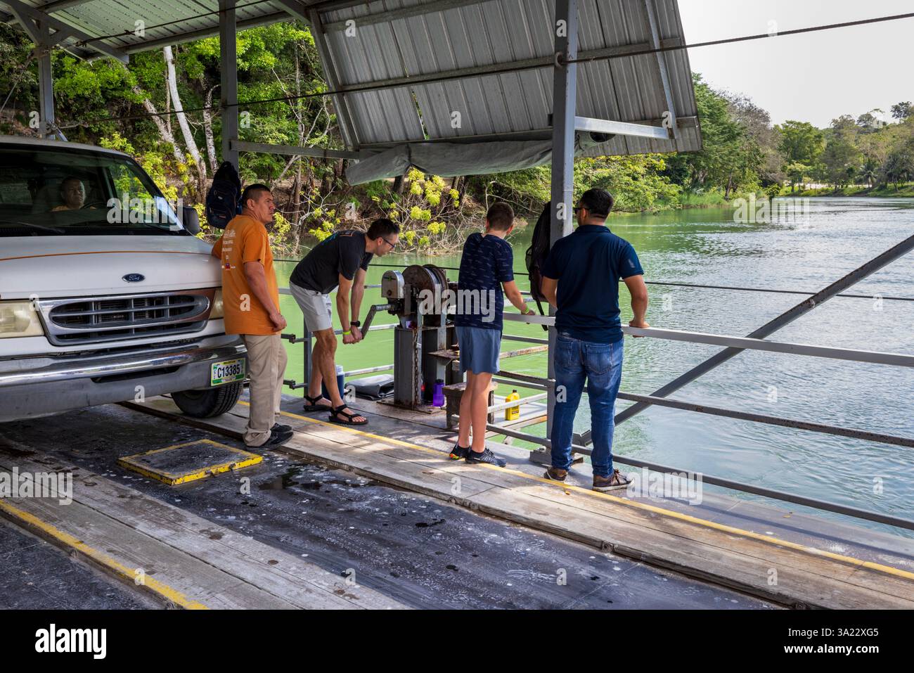 Tourists operating the winch on the Chain ferry across the Macal River ...