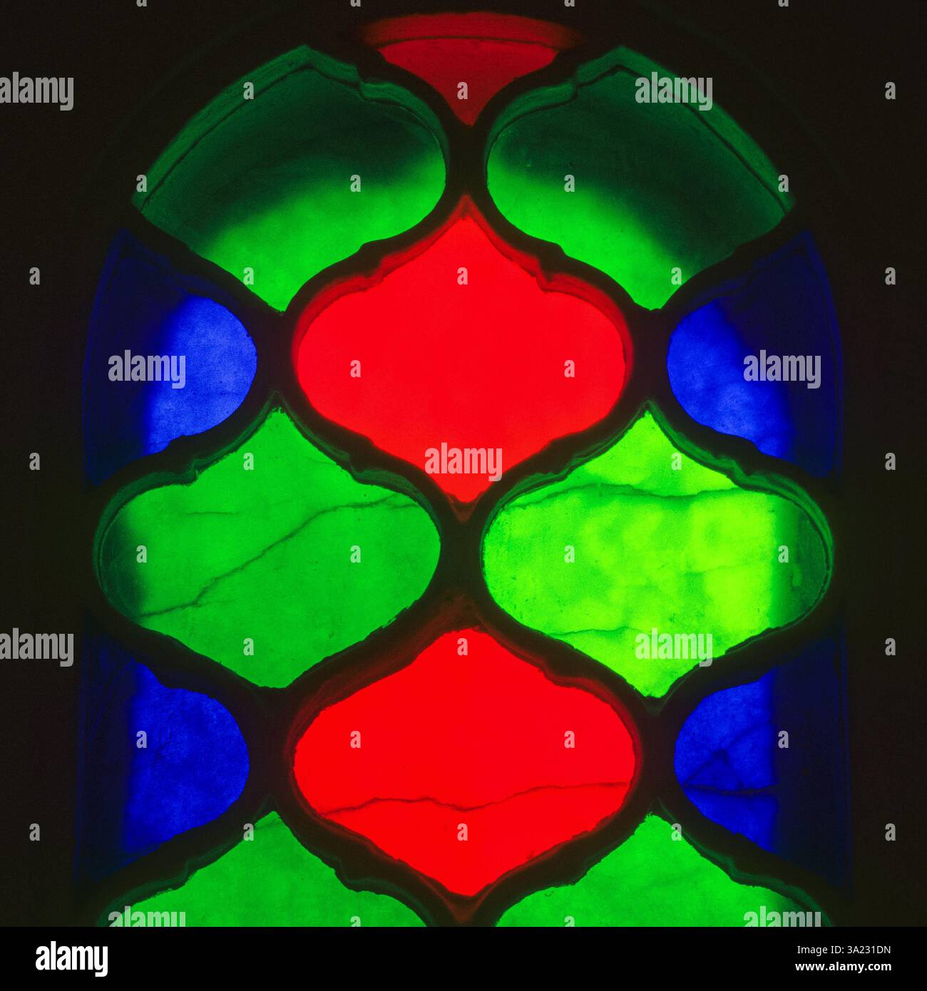 Curving red, blue and green stained glass shapes within the takhrim ...
