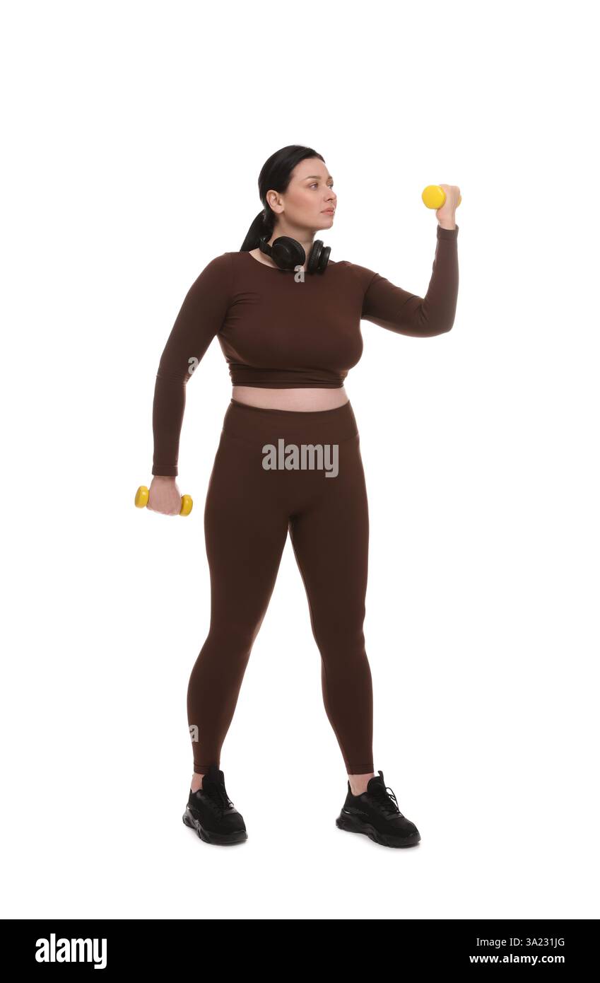 Plus size woman in gym clothes doing exercise with dumbbells on white ...