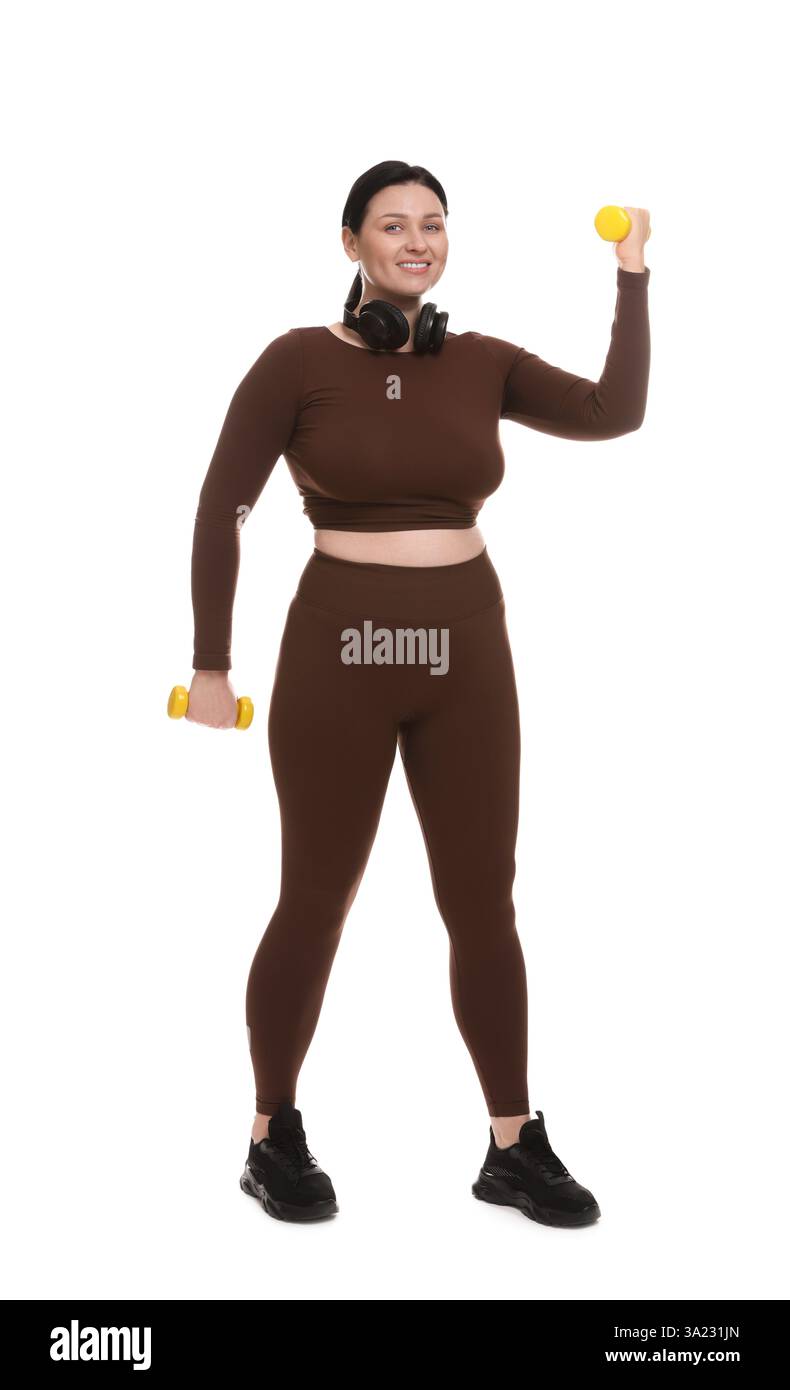 Plus size woman in gym clothes doing exercise with dumbbells on white ...