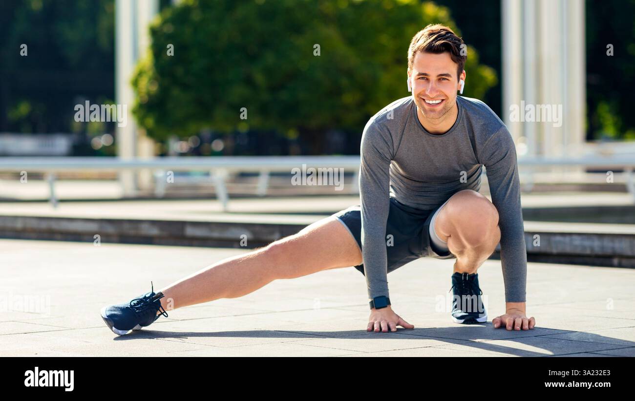 Warm up before run in park. Man in sports uniform doing leg exercises ...