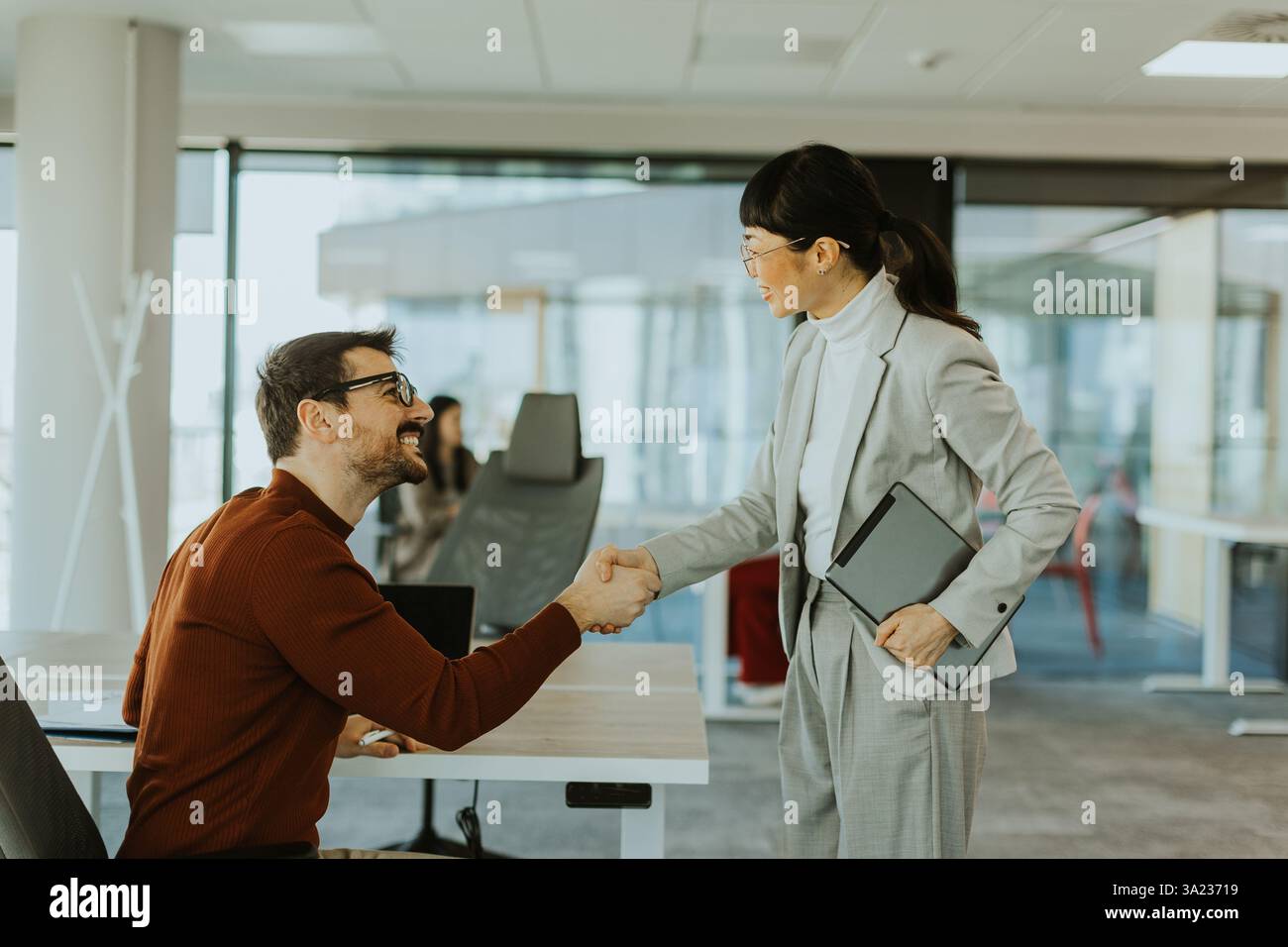 Two colleagues enjoy a moment of connection as they shake hands in a ...