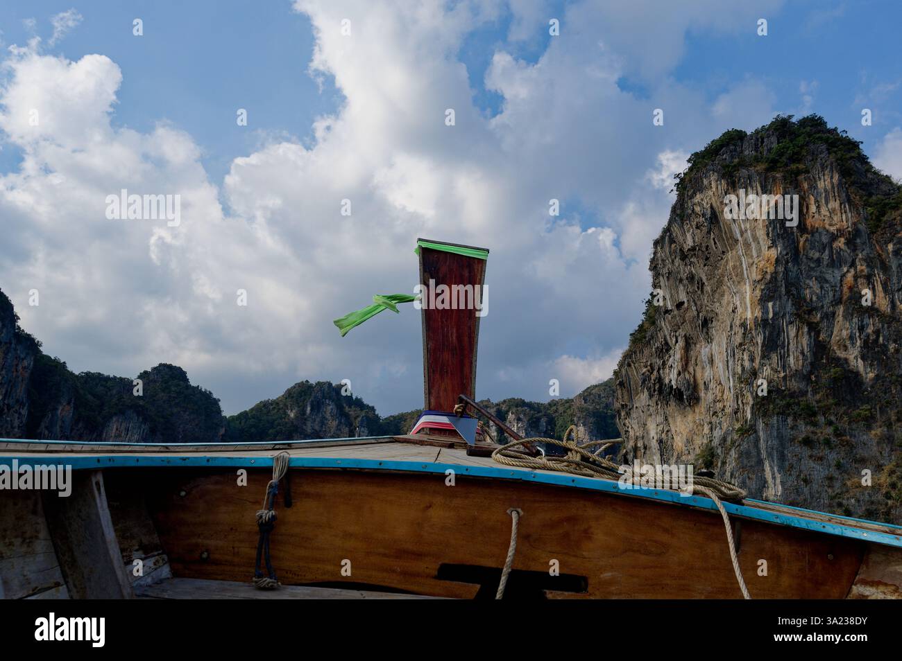 The bow of a traditional longtail boat points toward towering limestone ...