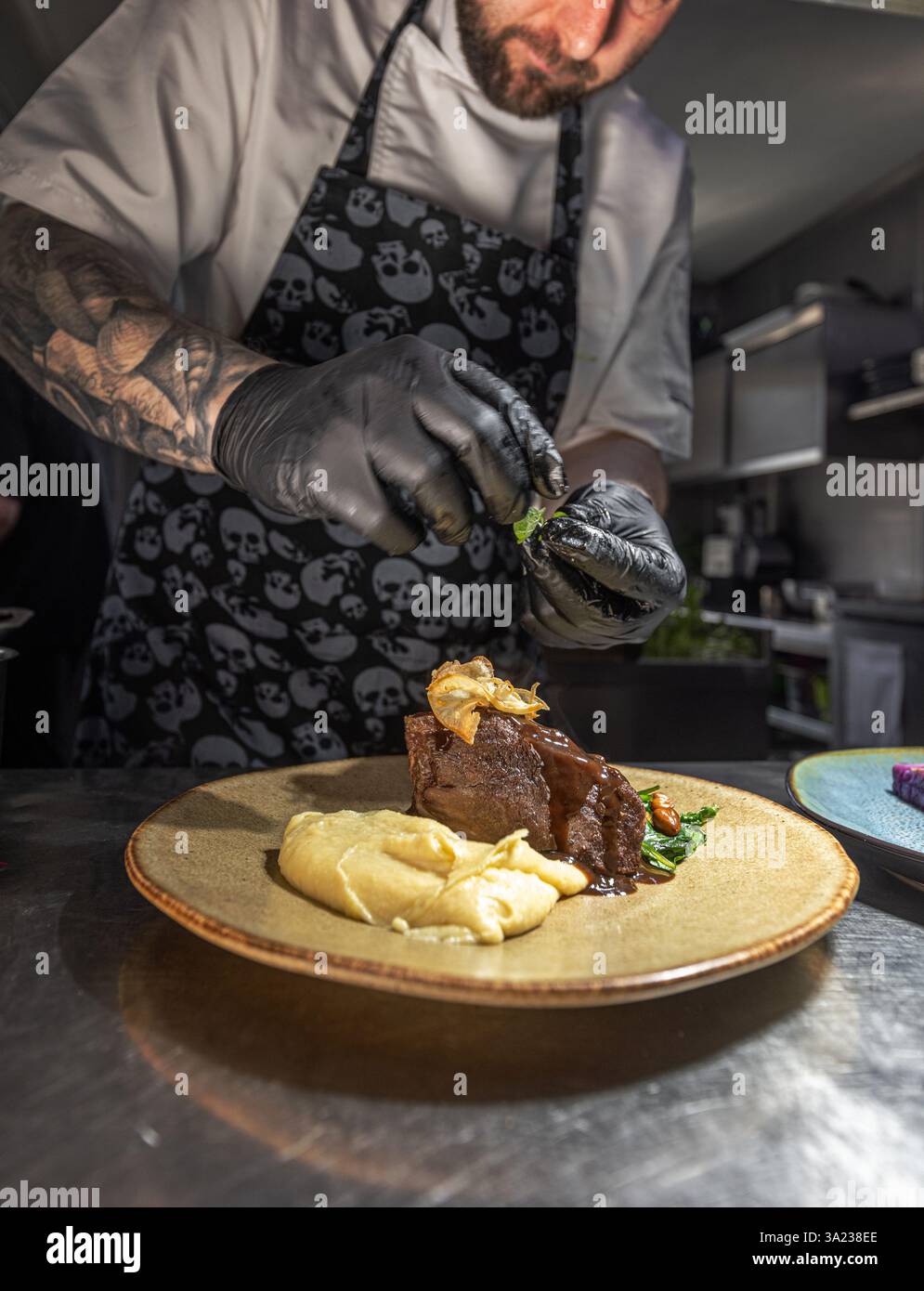 Professional chef adding final touch to a plated beef dish ...