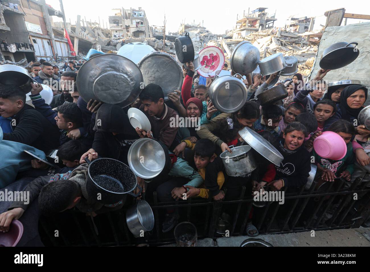 Displaced Palestinians queue to receive a share of food from a charity ...