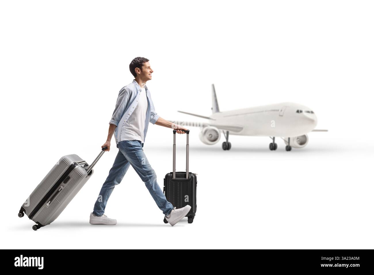 Full length profile shot of a young man pulling two suitcases at the ...