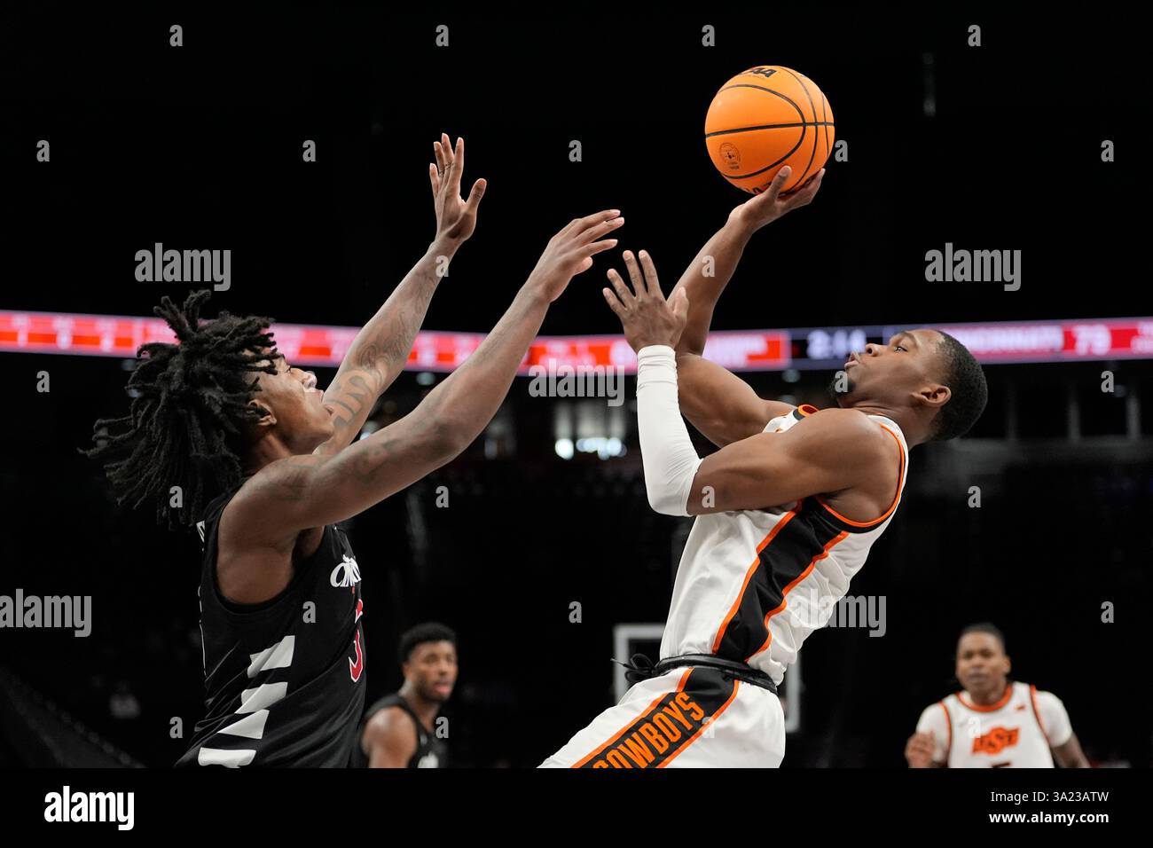 Oklahoma State's Brandon Newman, right, shoots over Cincinnati's Rayvon ...