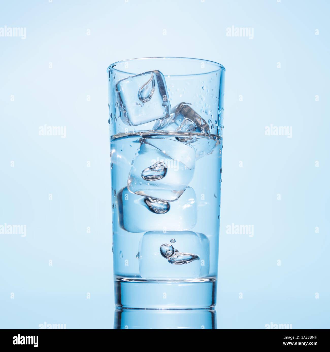 A clear glass filled with chilled water and ice cubes, creating a ...
