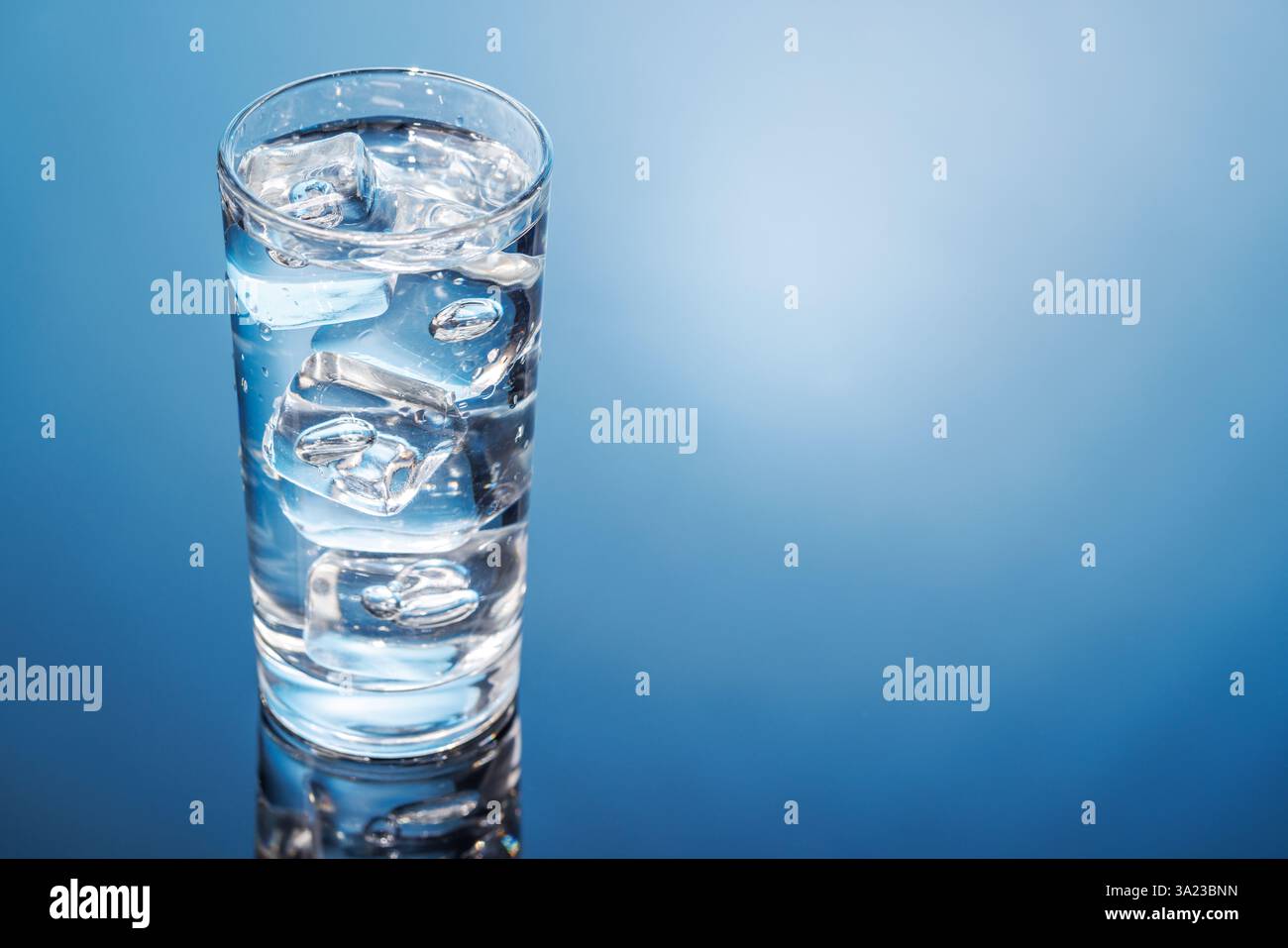 A clear glass filled with chilled water and ice cubes, creating a ...