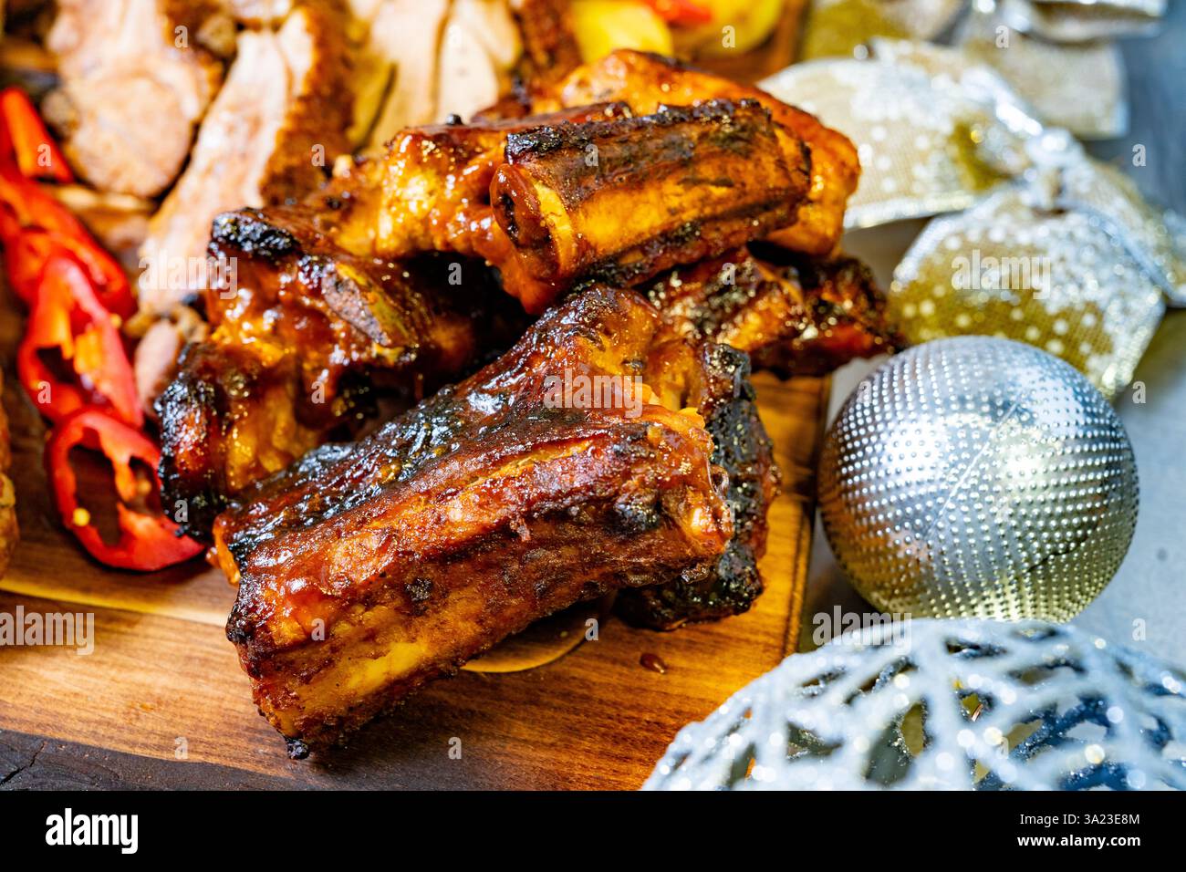 A platter displays juicy barbecue ribs alongside vibrant peppers and ...
