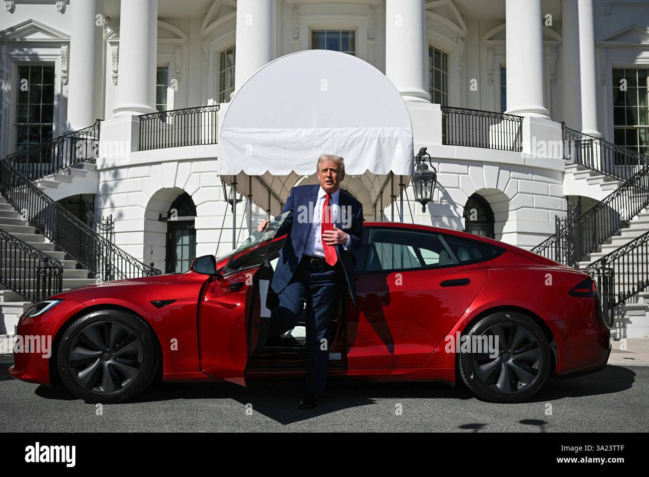 President Donald Trump steps out of a red Model S Tesla vehicle on the ...