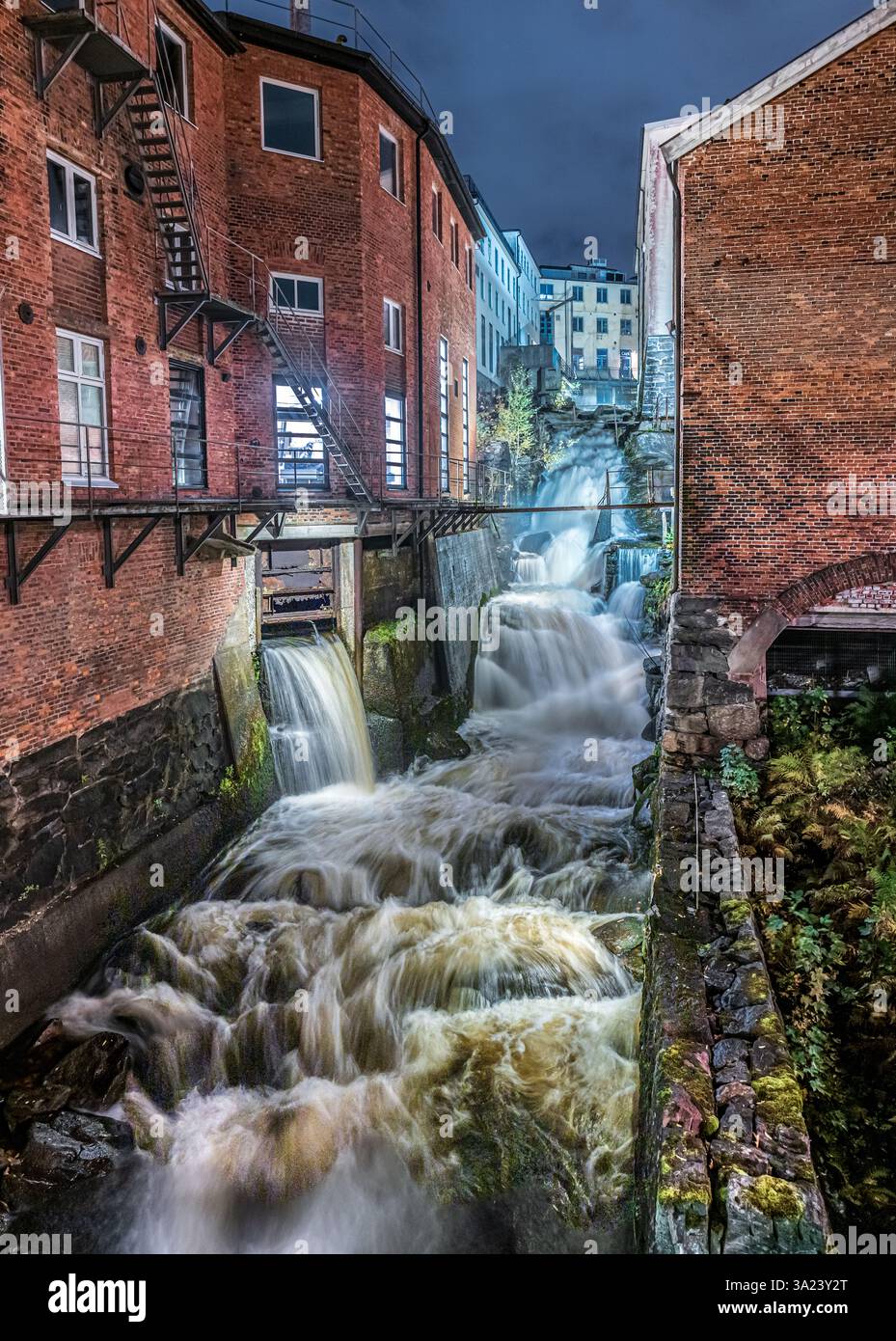 powerful rushing waterfall surrounded by industrial brick buildings ...