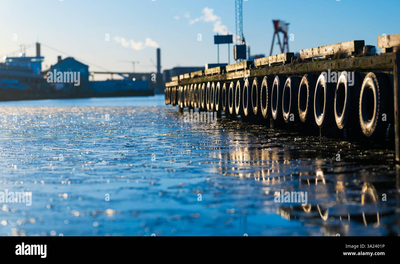 frozen harbor pier with reflections of industrial skyline Stock Photo ...