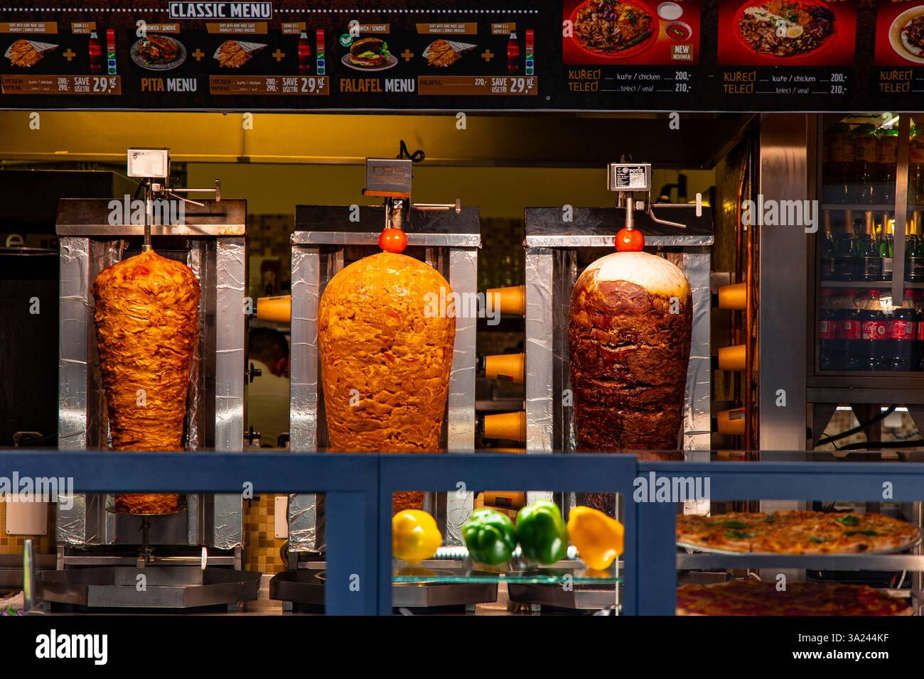 02-21-2025, Prague, Three rotating gyros grilling behind a glass, menu ...