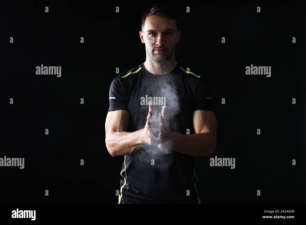 Man clapping hands with talcum powder before training on black ...