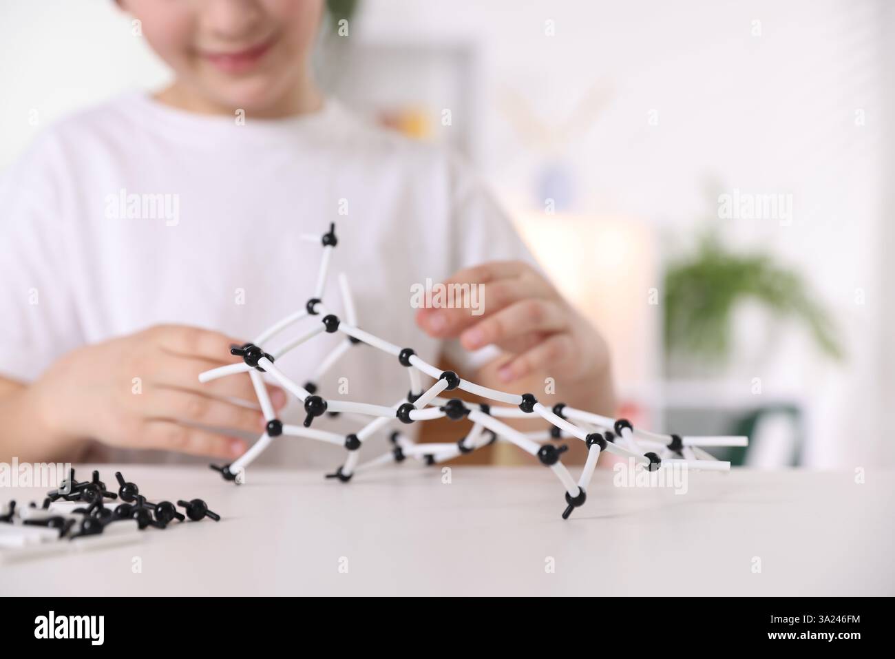 Boy making DNA structure model at desk indoors, closeup. Space for text ...