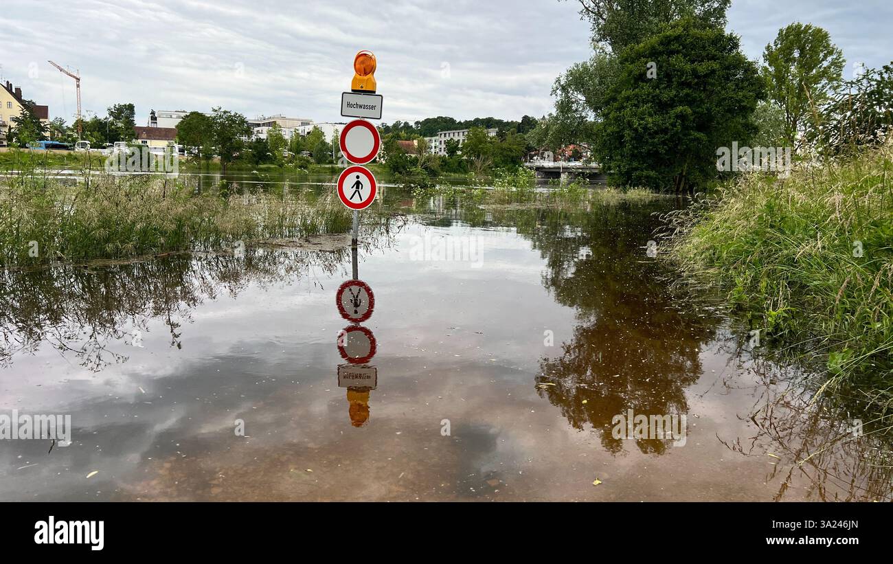 A flooded walkway in Regensburg with traffic signs partially submerged ...