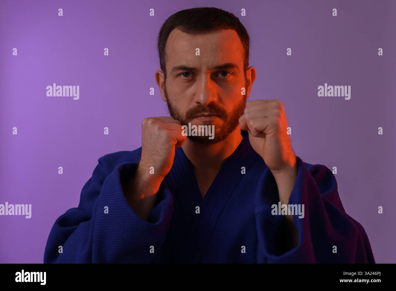 Karate fighter wearing uniform in color lights against violet ...