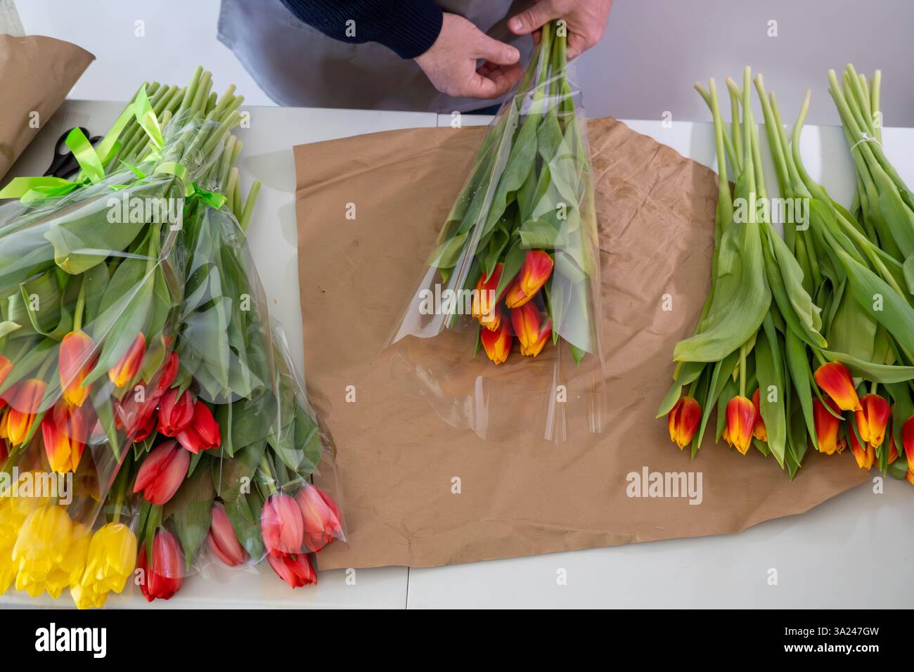 Florist arranging colorful tulip bouquets on wrapping paper Stock Photo ...
