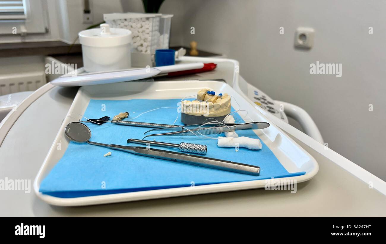 A set of dental tools, including a mirror and forceps, placed on a ...