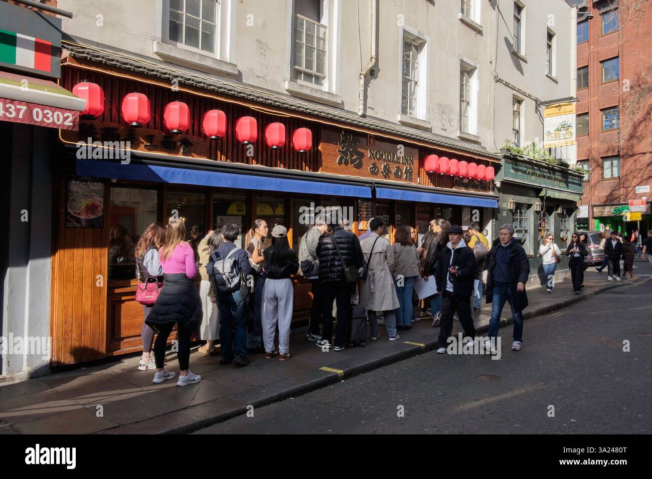 Customer queue outside Noodle Inn, Old Compton Street, Soho, London, UK ...