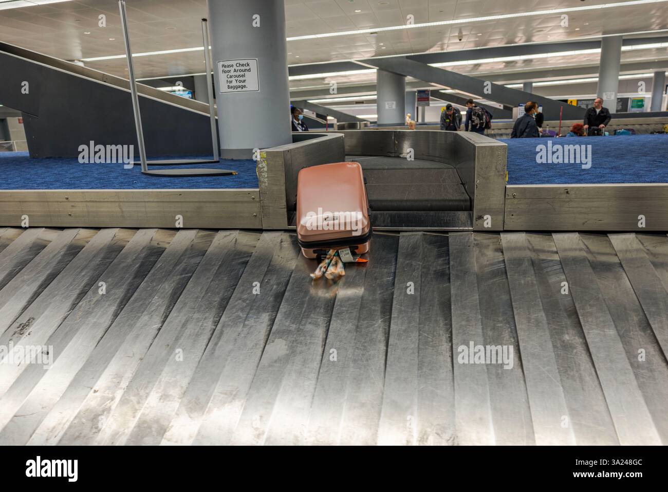 Suitcase emerging onto baggage carousel at airport terminal as ...