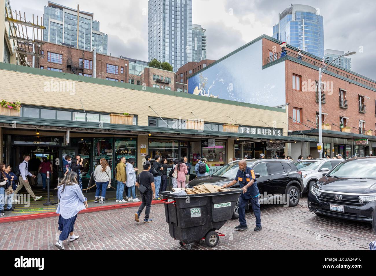 A worker collects cardboard at Pike Place Market, Seattle. Tourists ...
