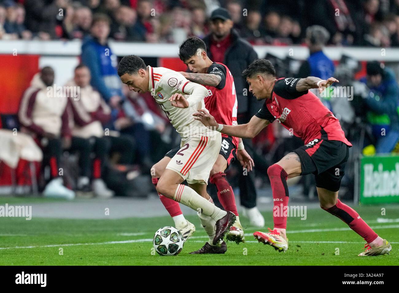 Bayern's Jamal Musiala, left, duels for the ball with Leverkusen's Exequiel Palacios, center ...