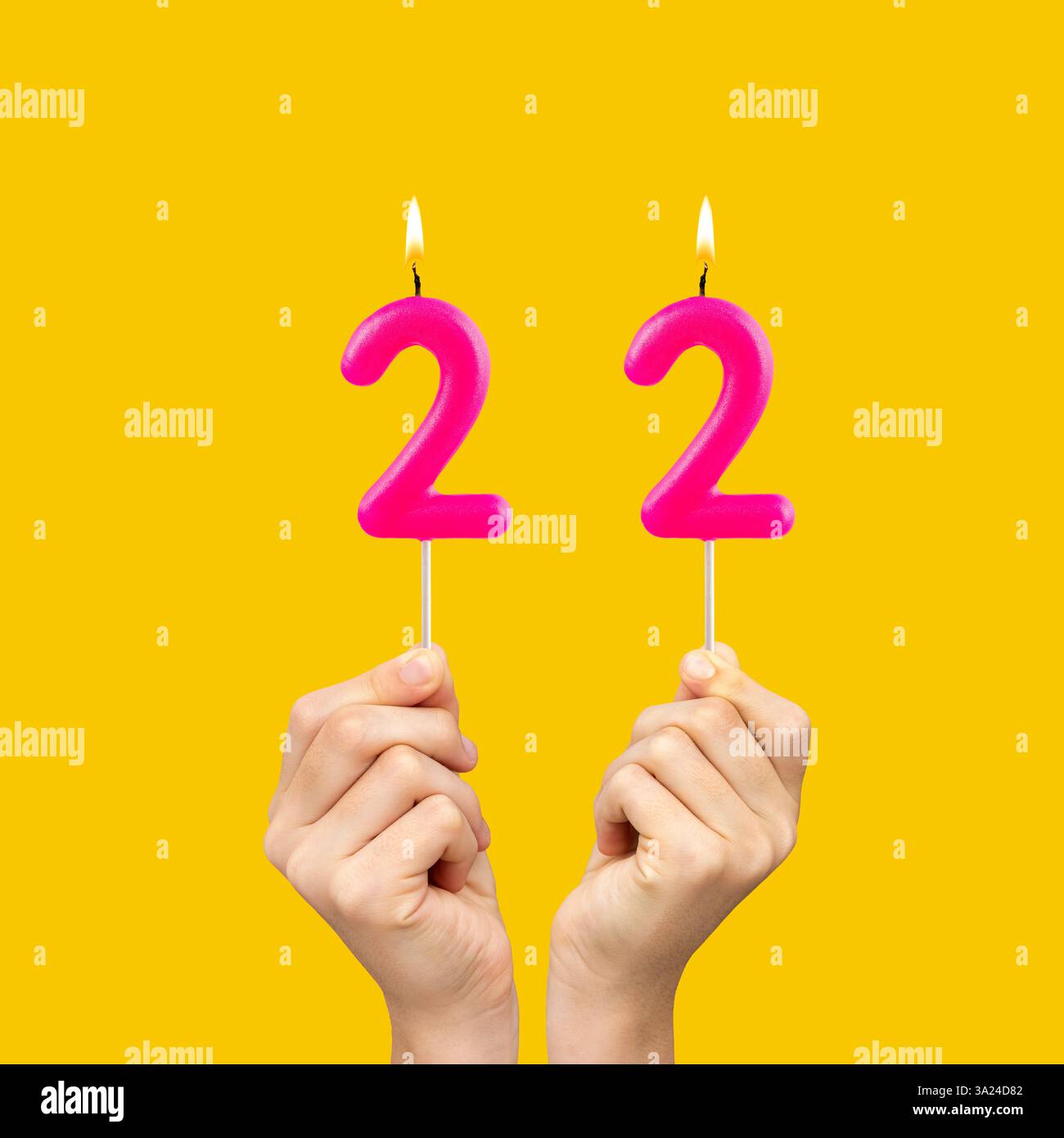 Hands holding birthday candles with number 22 - Yellow background Stock ...
