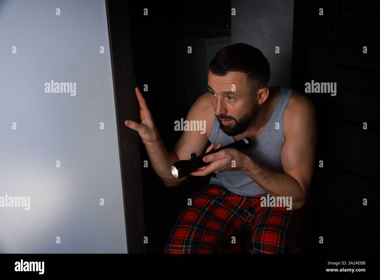 Fear of darkness. Scared man with flashlight in room at night Stock ...