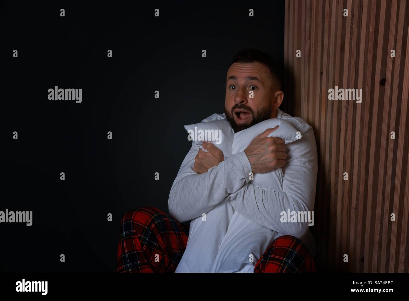 Fear of darkness. Scared man hugging pillow indoors at night Stock ...