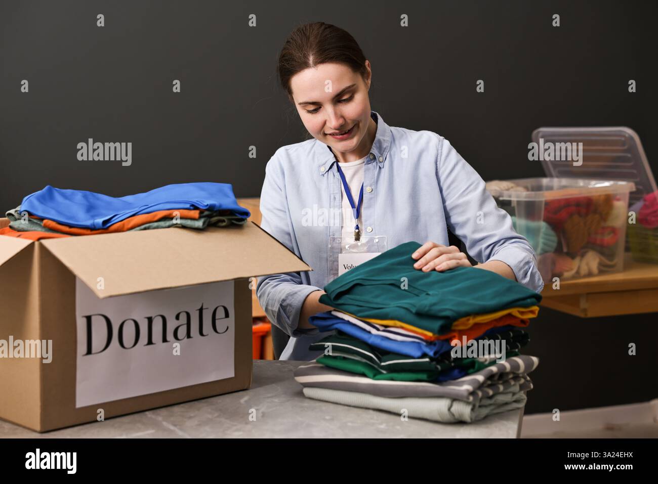 Volunteer sorting clothes for donation at table indoors Stock Photo - Alamy
