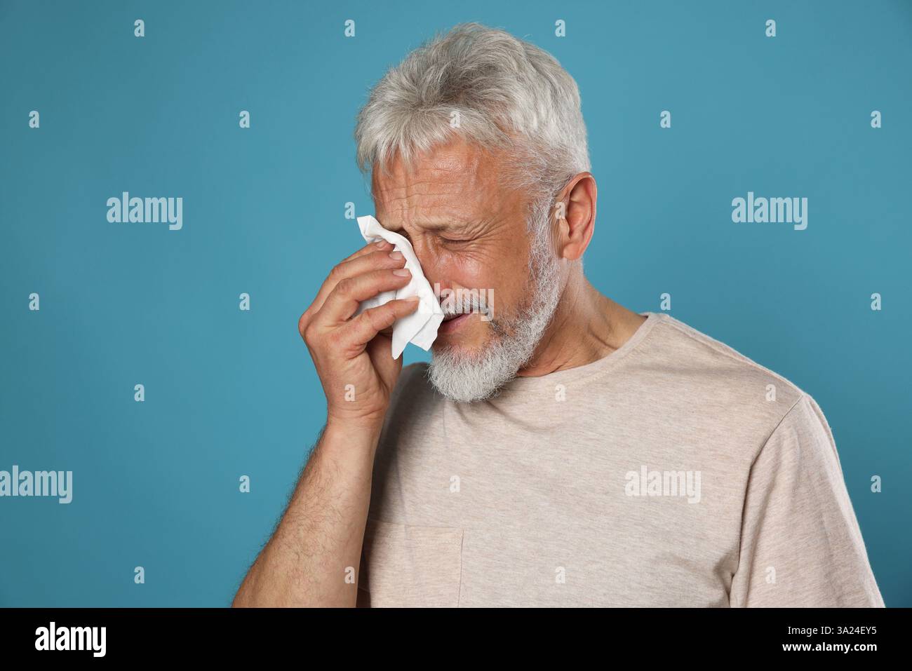 Sad senior man crying on light blue background Stock Photo - Alamy